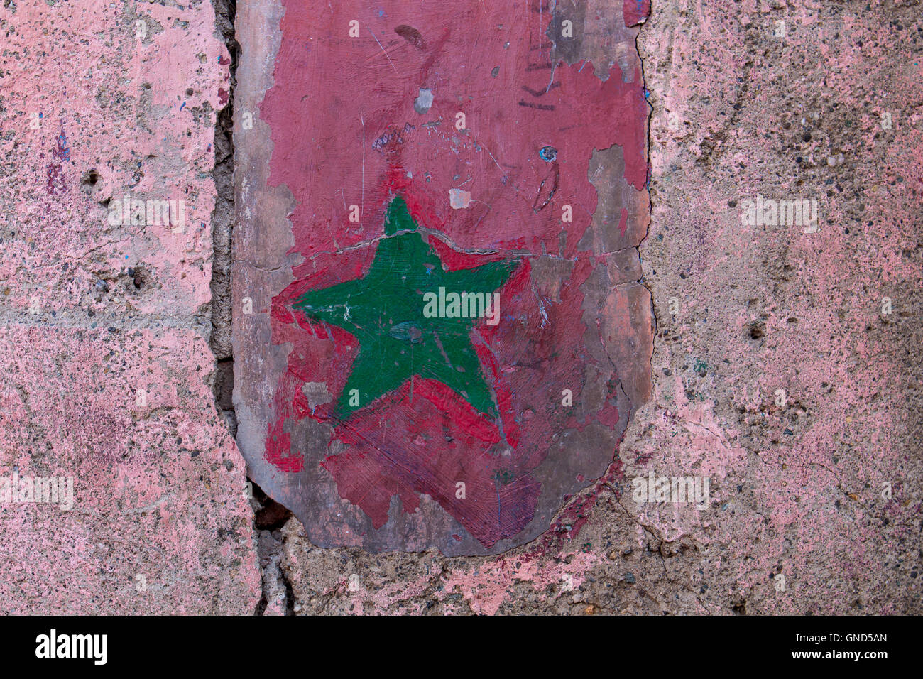 Old wall loosing its original color, with a sign of a moroccan flag ...