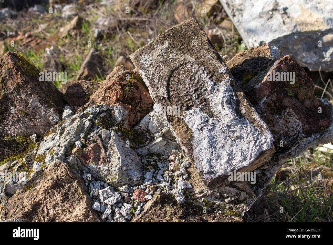 Brick on the pile of rubbish, partly dirty from cement. Still visible ...