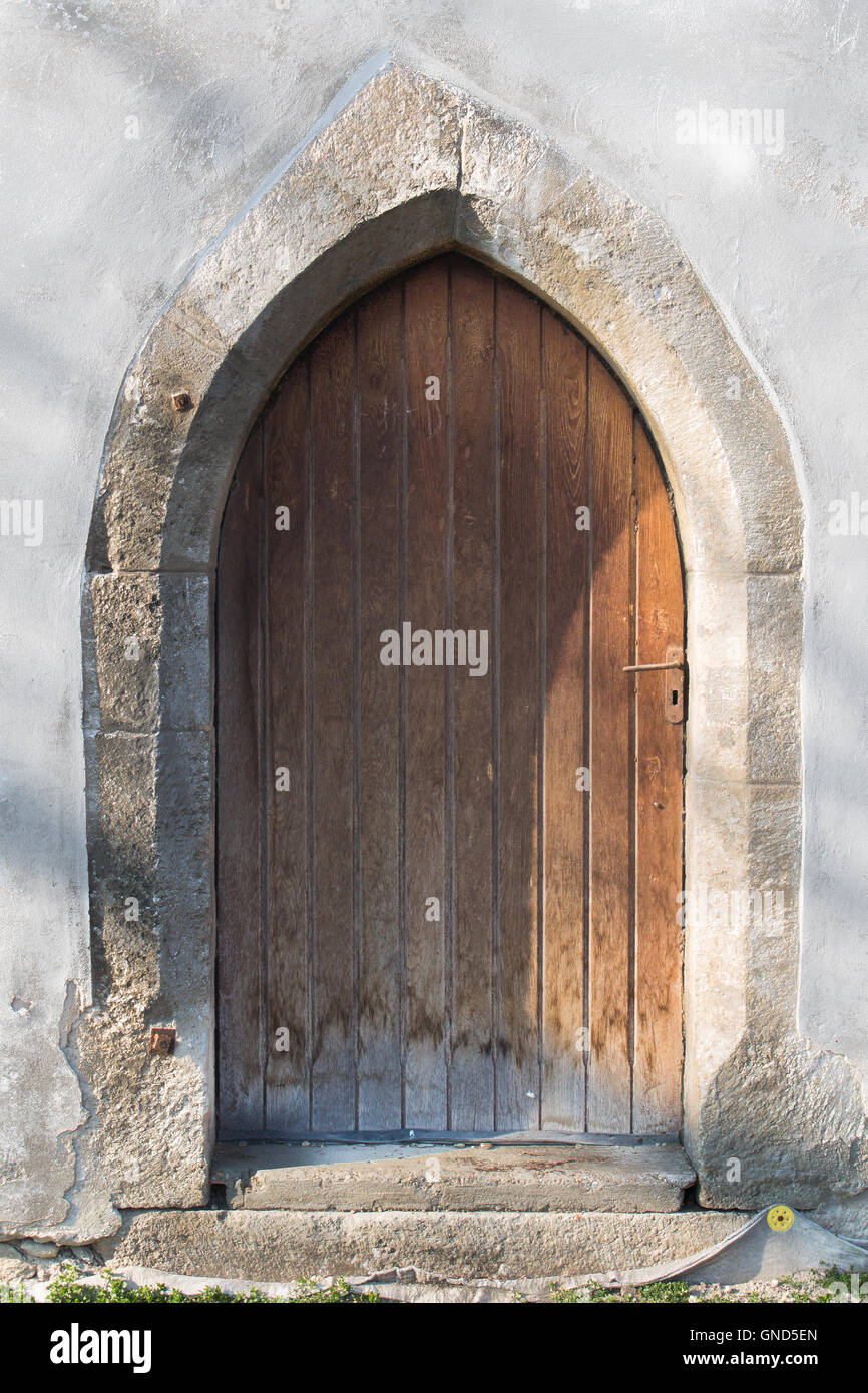 Gothic gate with a stone frame and wooden heavy door. Church of Saint ...