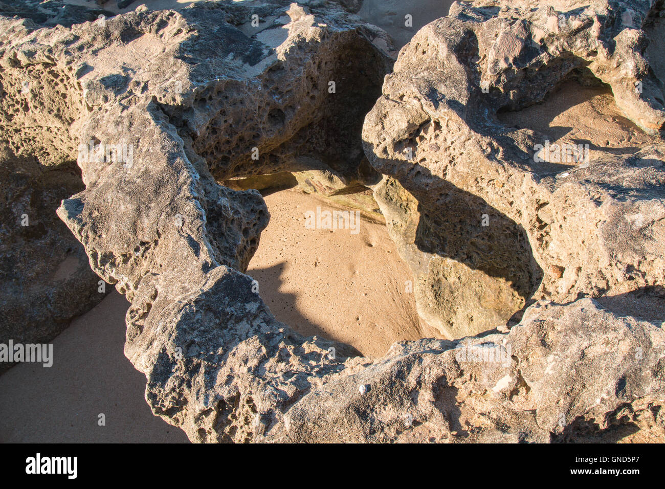 Rocks with sharp edges and holes on the beach of Atlantic Ocean in ...