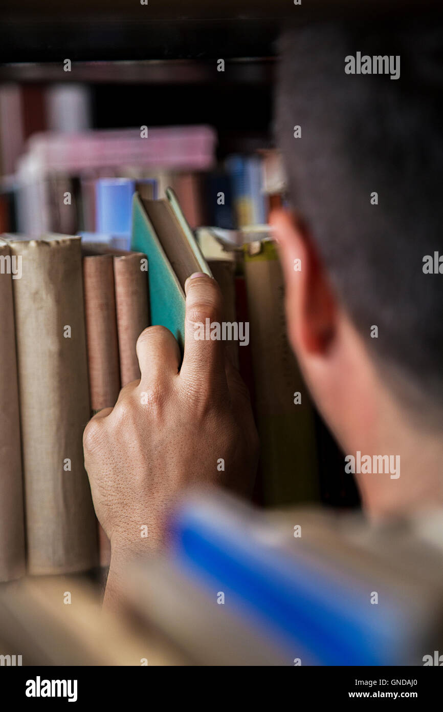Young man picking a book in the library Stock Photo - Alamy