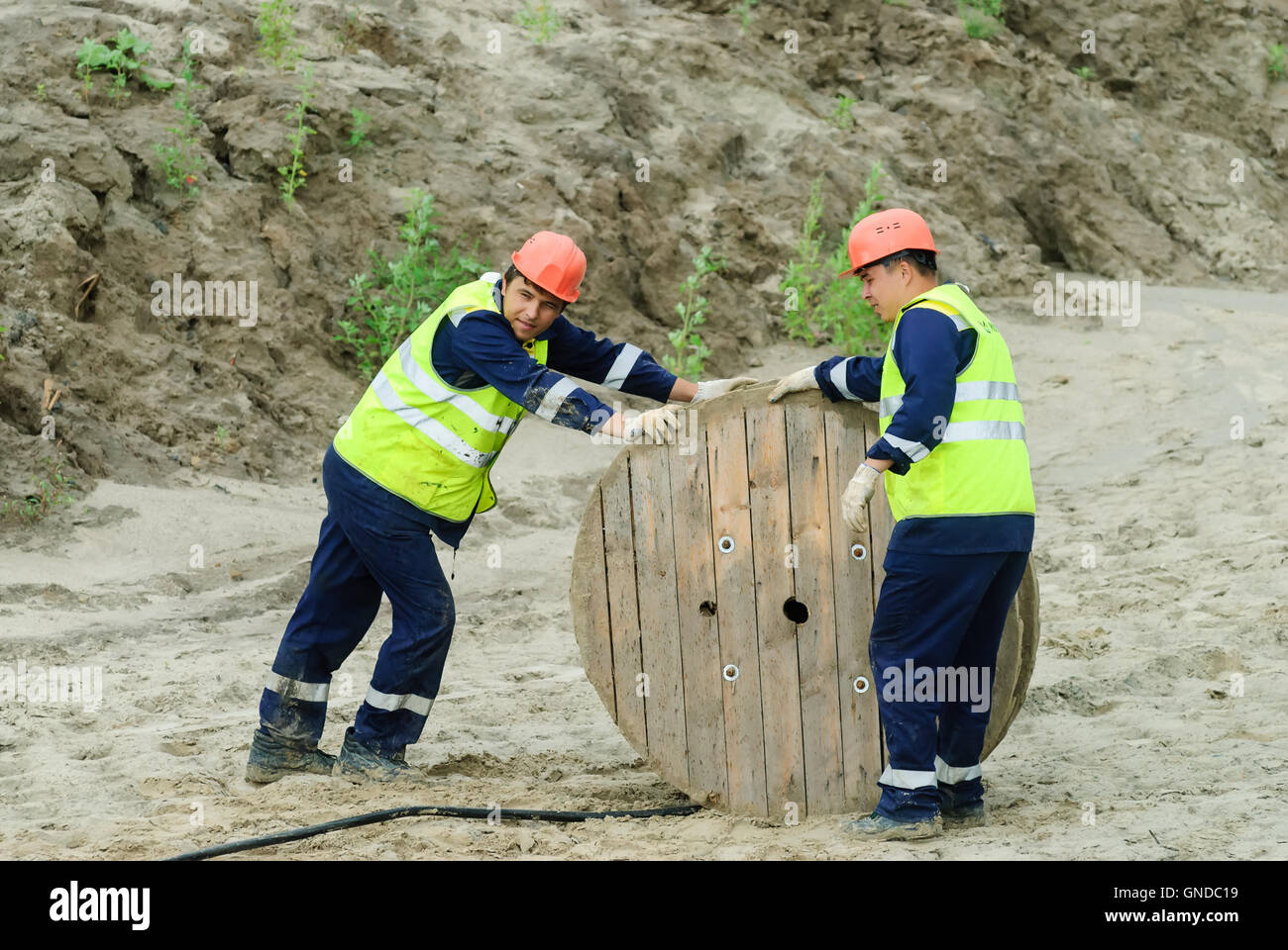 Workers pulling roll high voltage cable line Stock Photo - Alamy