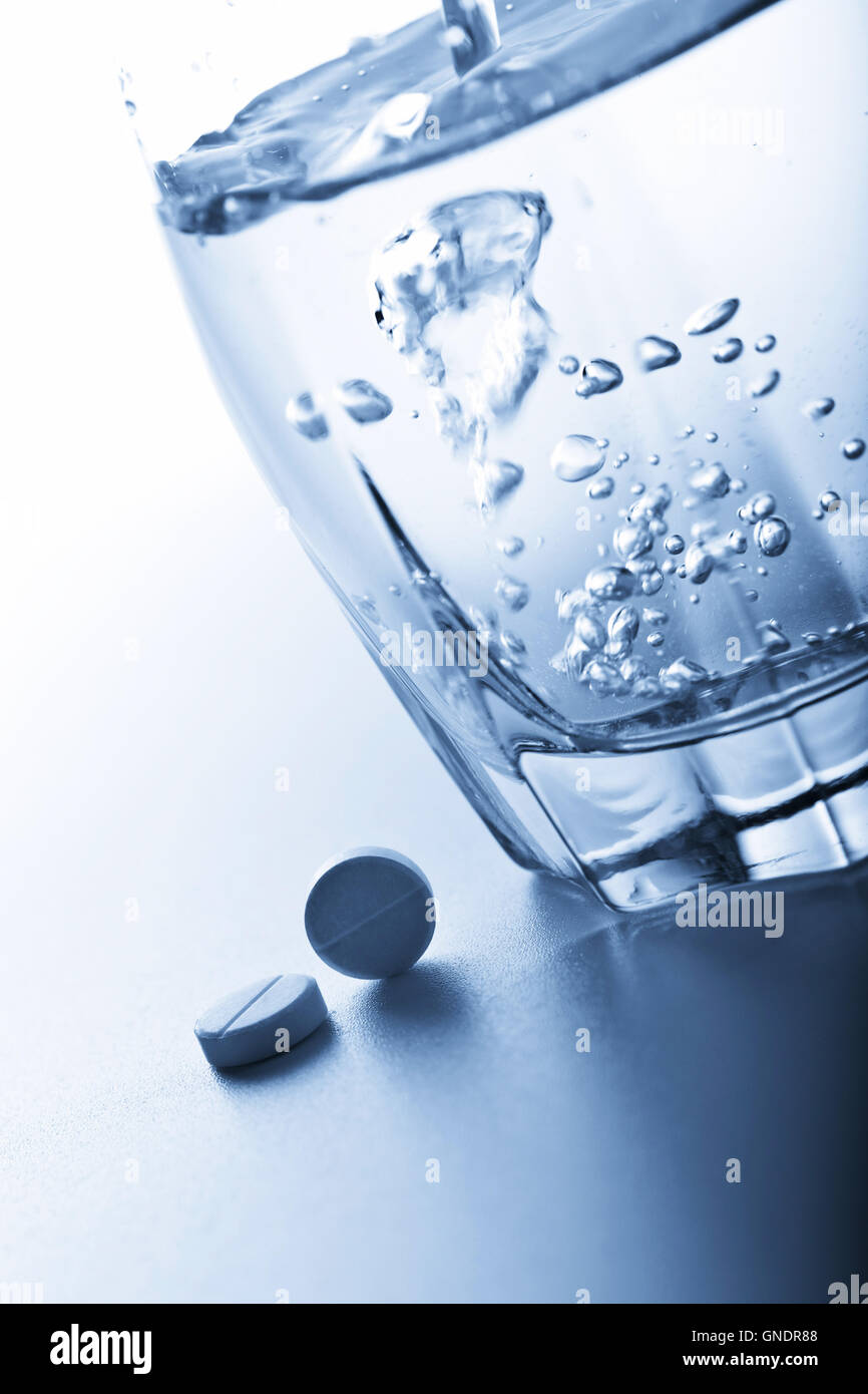 aspirin pills and glass of water toned blue Stock Photo - Alamy