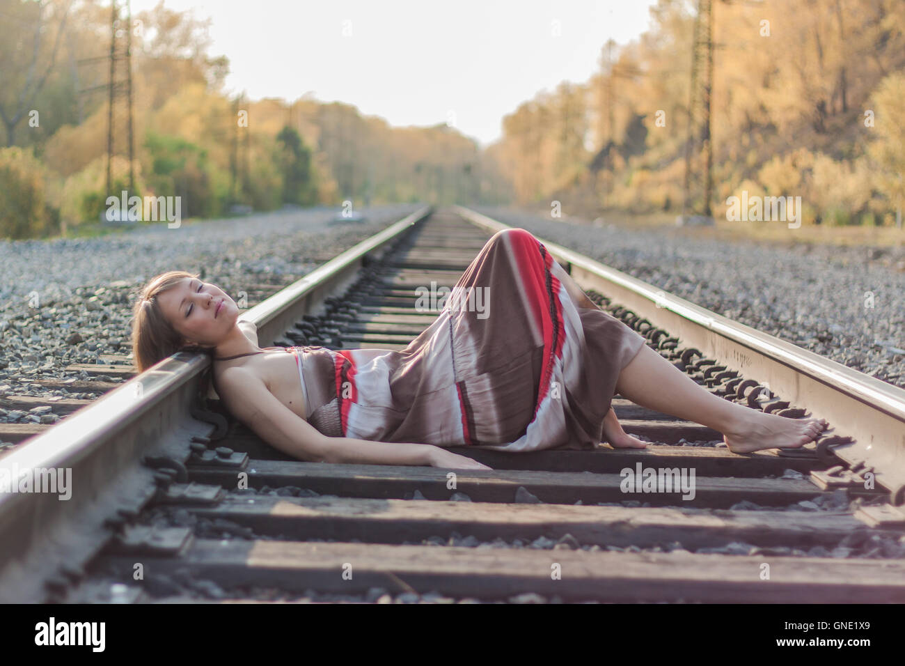 Beautiful girl laying on railroad track Stock Photo - Alamy