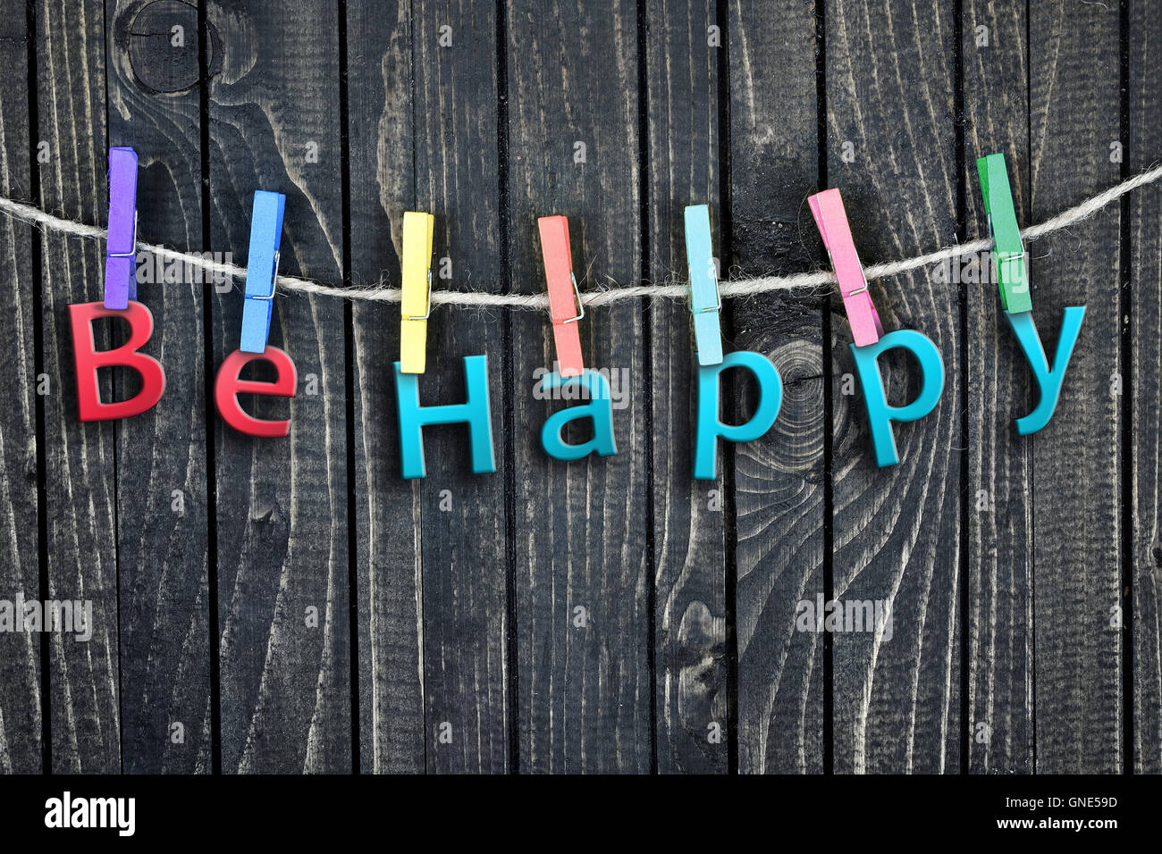 Be Happy word hanging on clips and wooden wall Stock Photo - Alamy