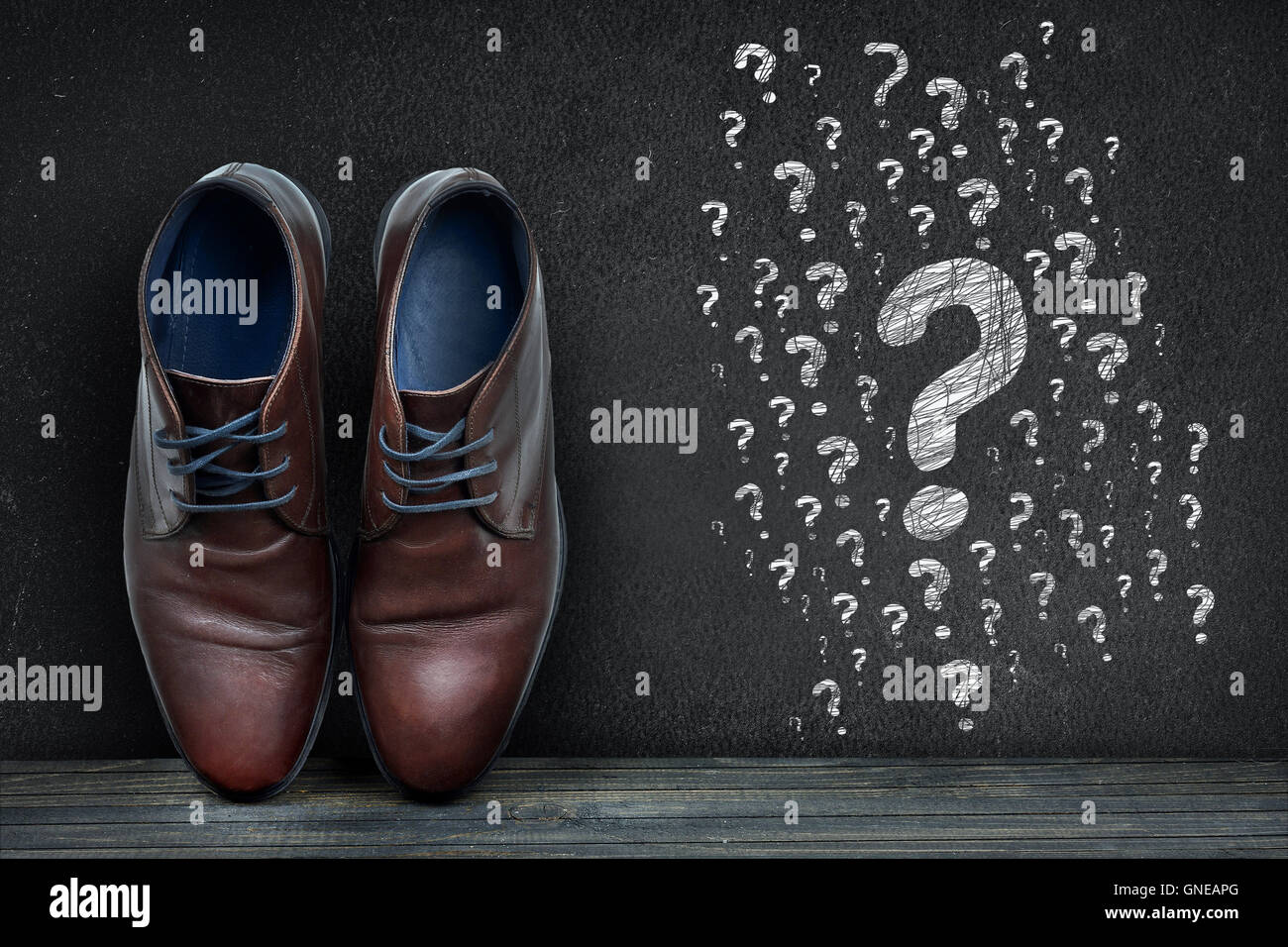 Question marks text on black board and business shoes on wooden floor ...