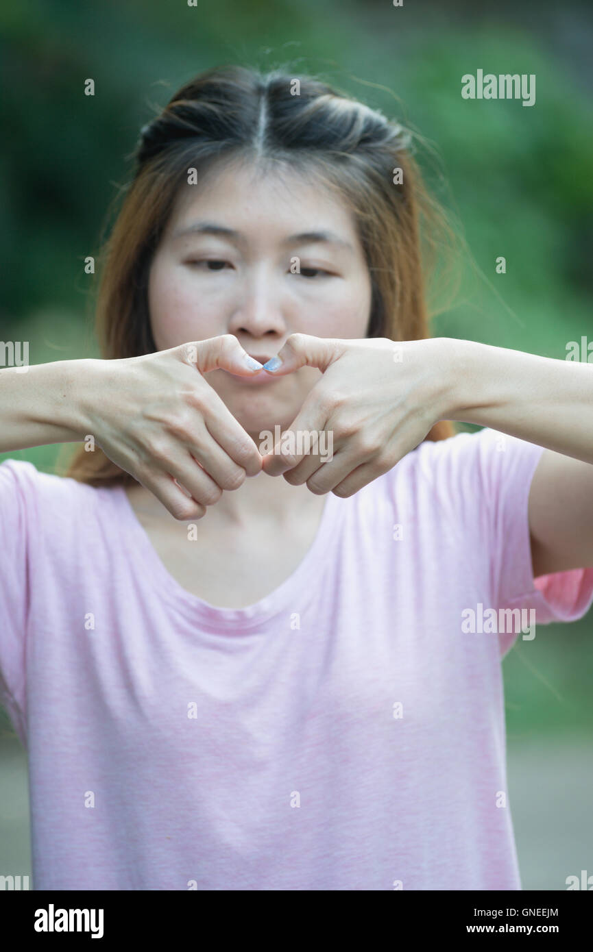 asia smiling cheerful young woman making heart sign with hands ...