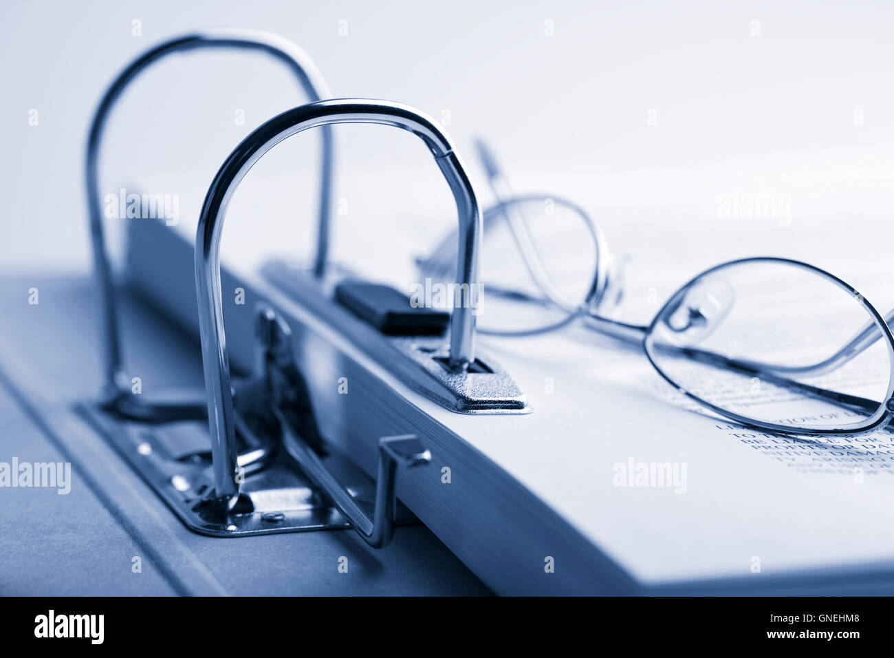 open binder and glasses over document toned blue Stock Photo - Alamy