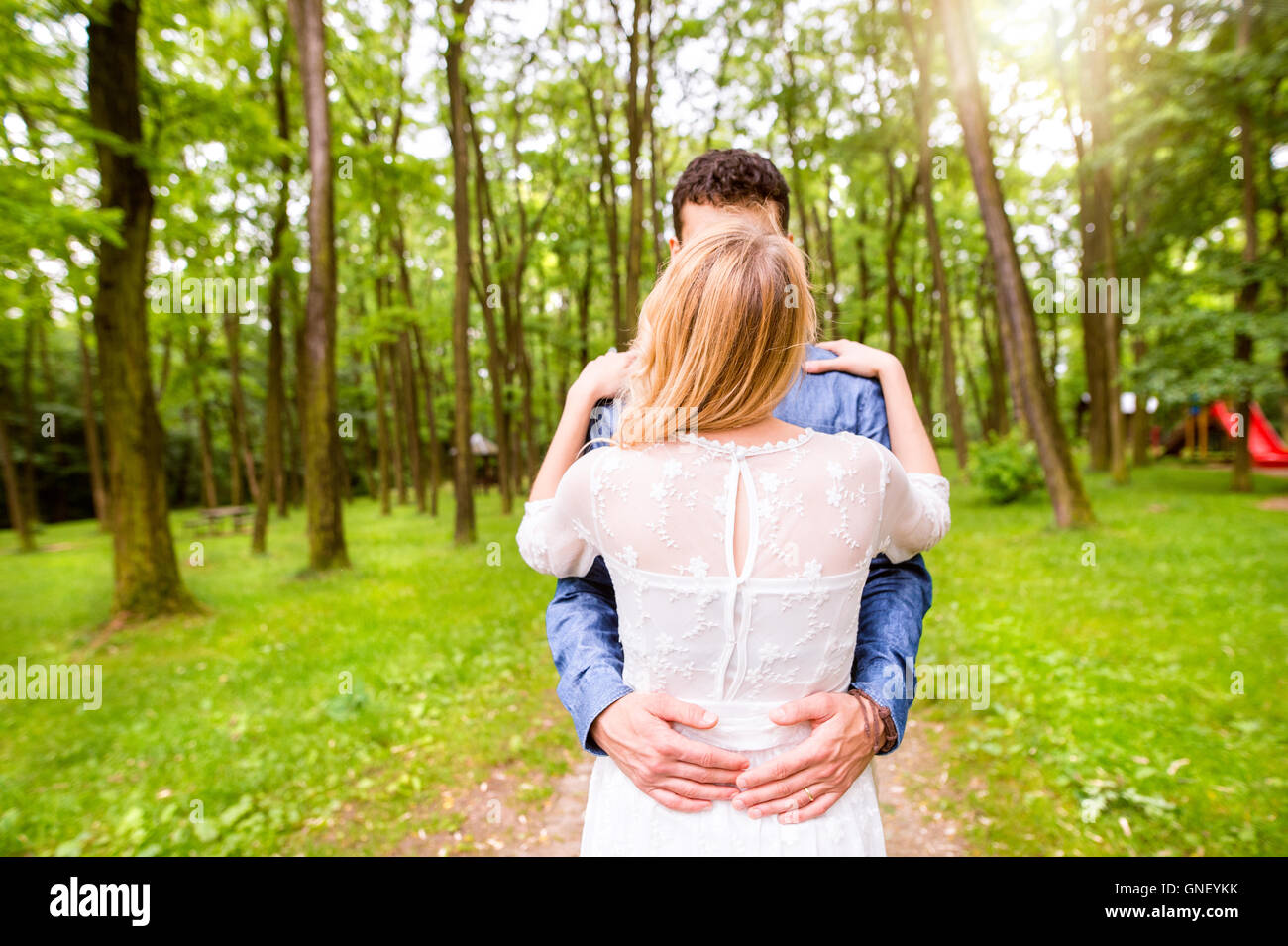 Beautiful wedding couple outside in green forest. Rear view Stock Photo ...