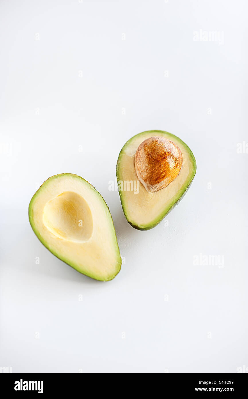 Avocado cut in half with pit seed on white background Stock Photo - Alamy