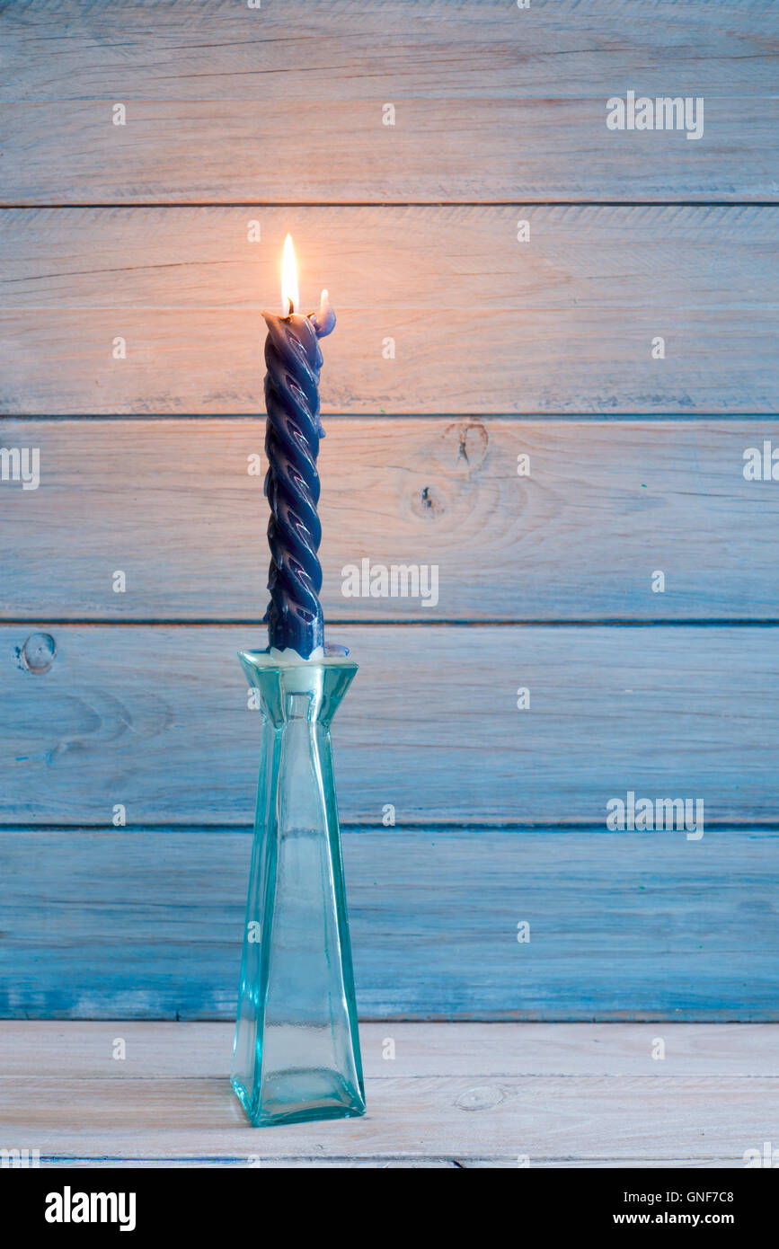 lit candle, blue wood background. Copy space Stock Photo - Alamy