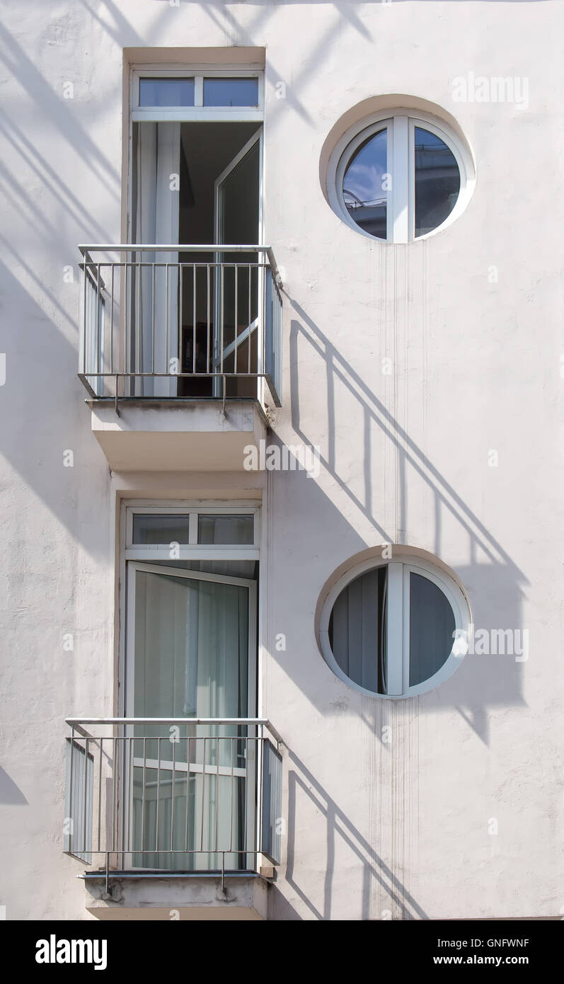 Detail of a white building with two balconies and circle windows. Lines ...