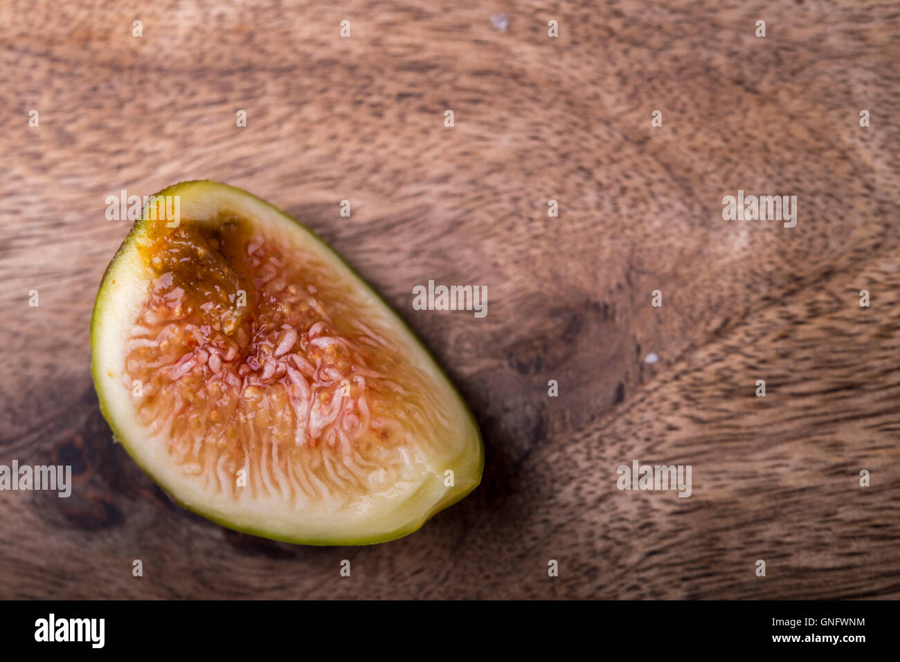 slice of fig isolated on wooden background Stock Photo - Alamy