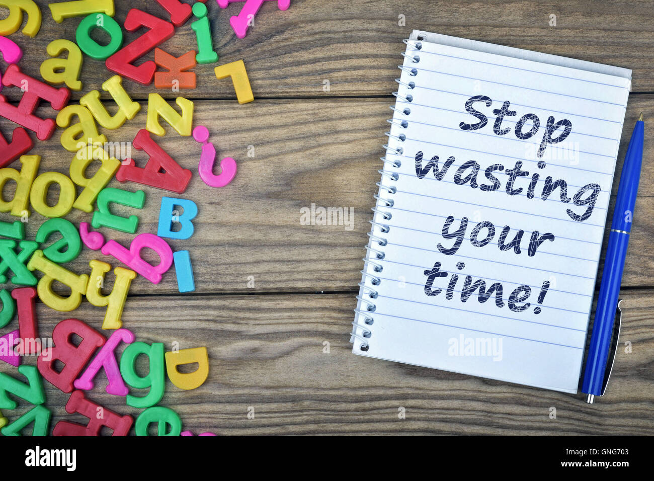 Stop wasting time text on notepad and magnetic letters on wooden table ...