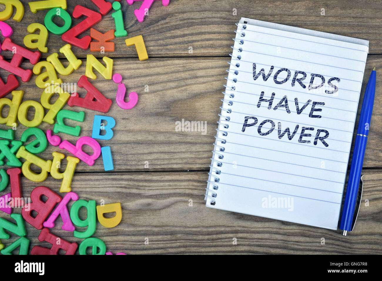 Words have power text on notepad and magnetic letters on wooden table ...