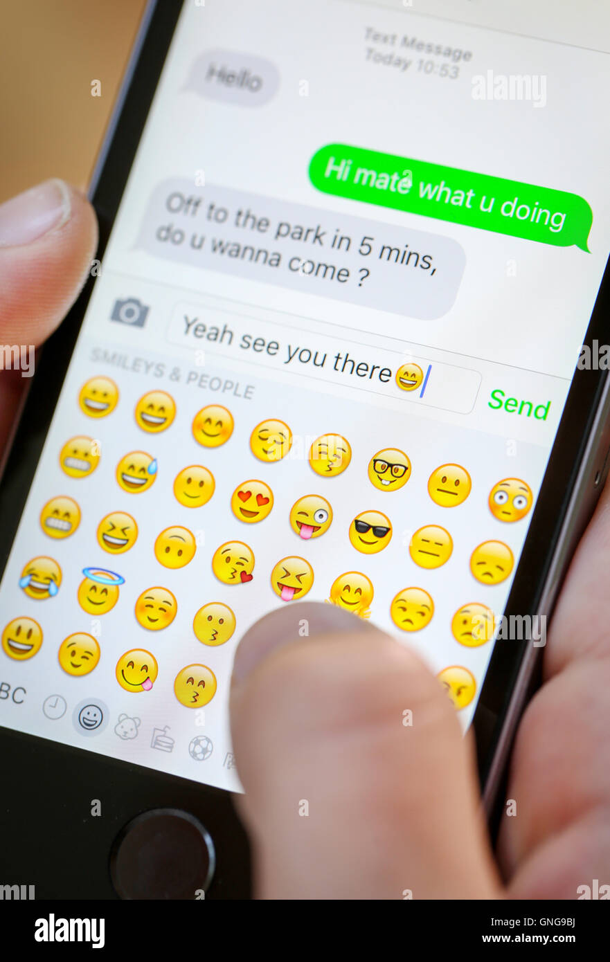 A teenage boy using an emoji whilst texting on his iphone Stock Photo ...