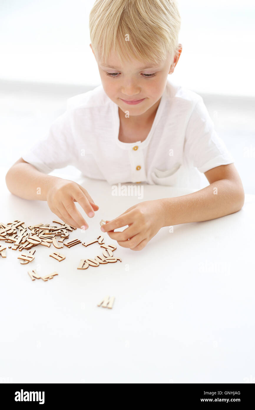 Learning to write. The child puts words with letters Stock Photo - Alamy