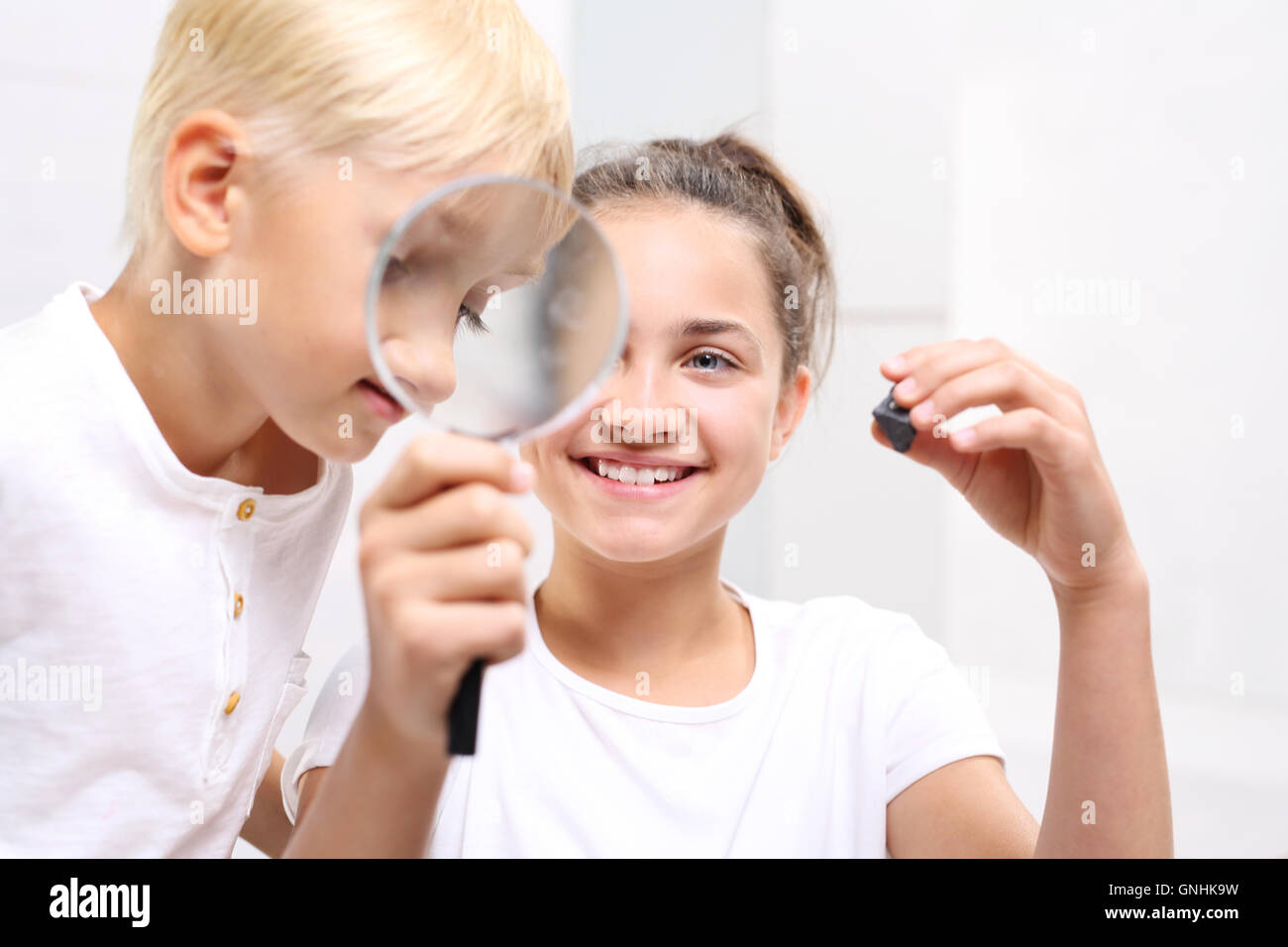 Siblings watching through a magnifying glass rock Two children, a girl ...