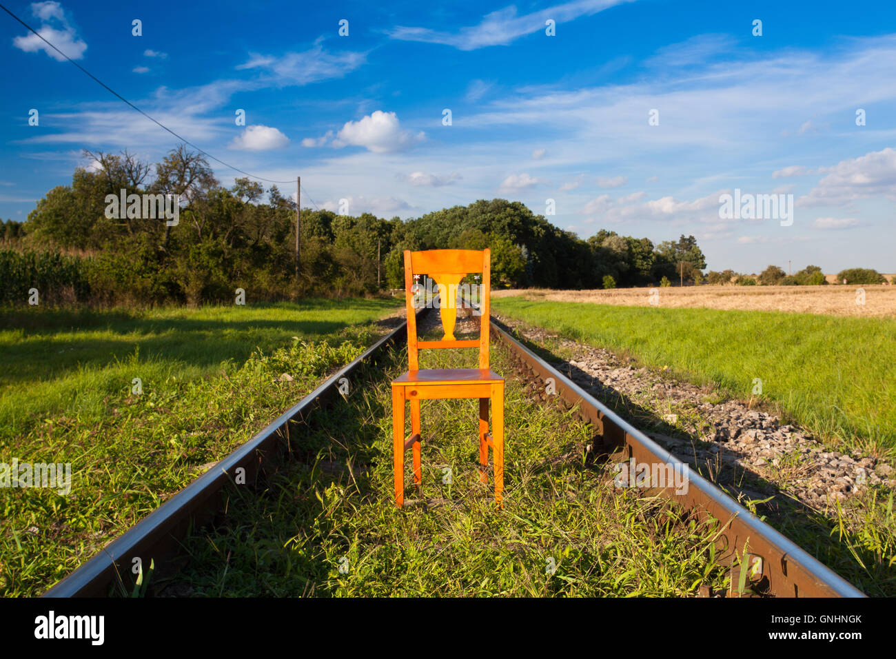 Railroad tracks and old wooden chair at sunset Stock Photo - Alamy