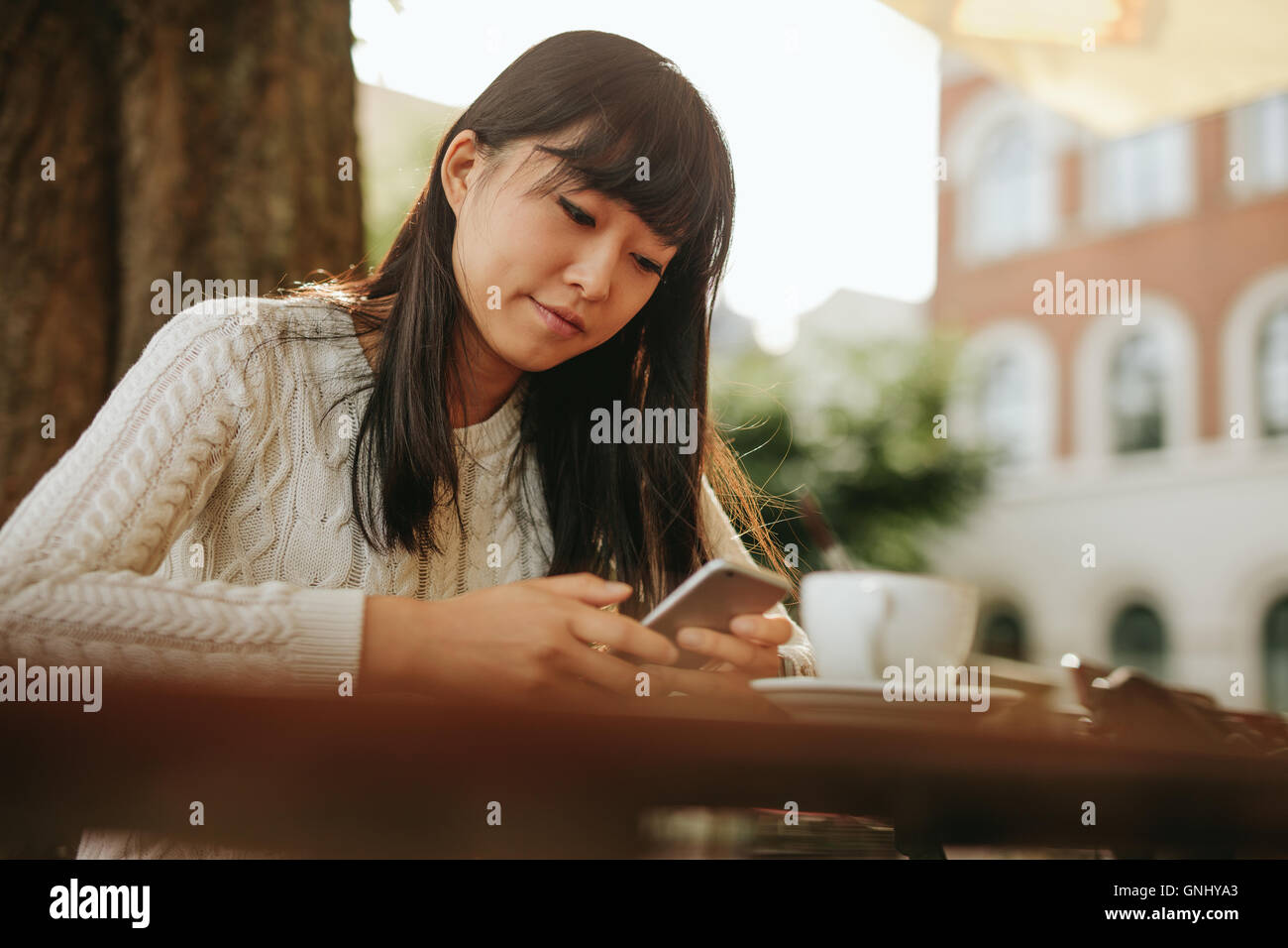 Chinese woman typing text message on smart phone in a cafe. Image of ...