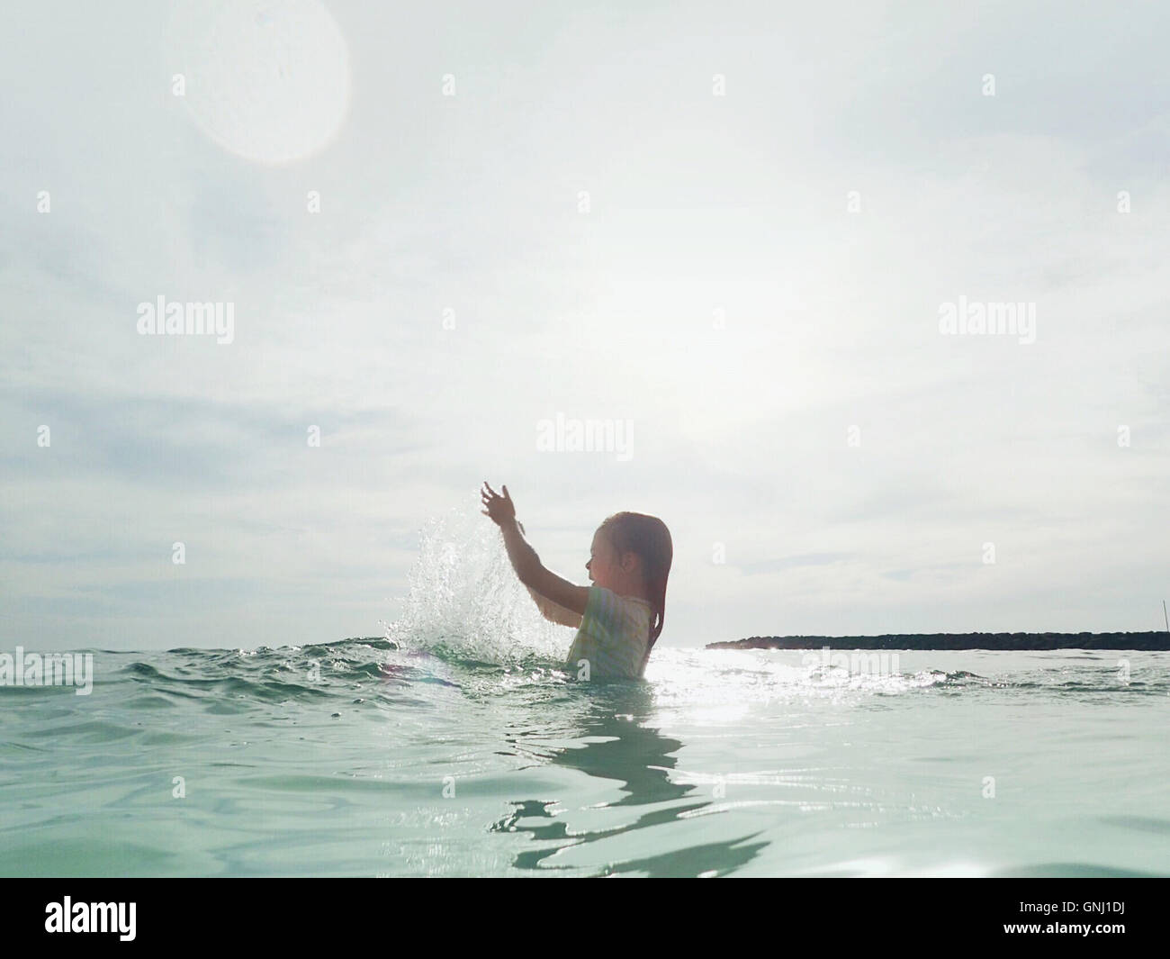 Girl splashing about in the sea Stock Photo - Alamy