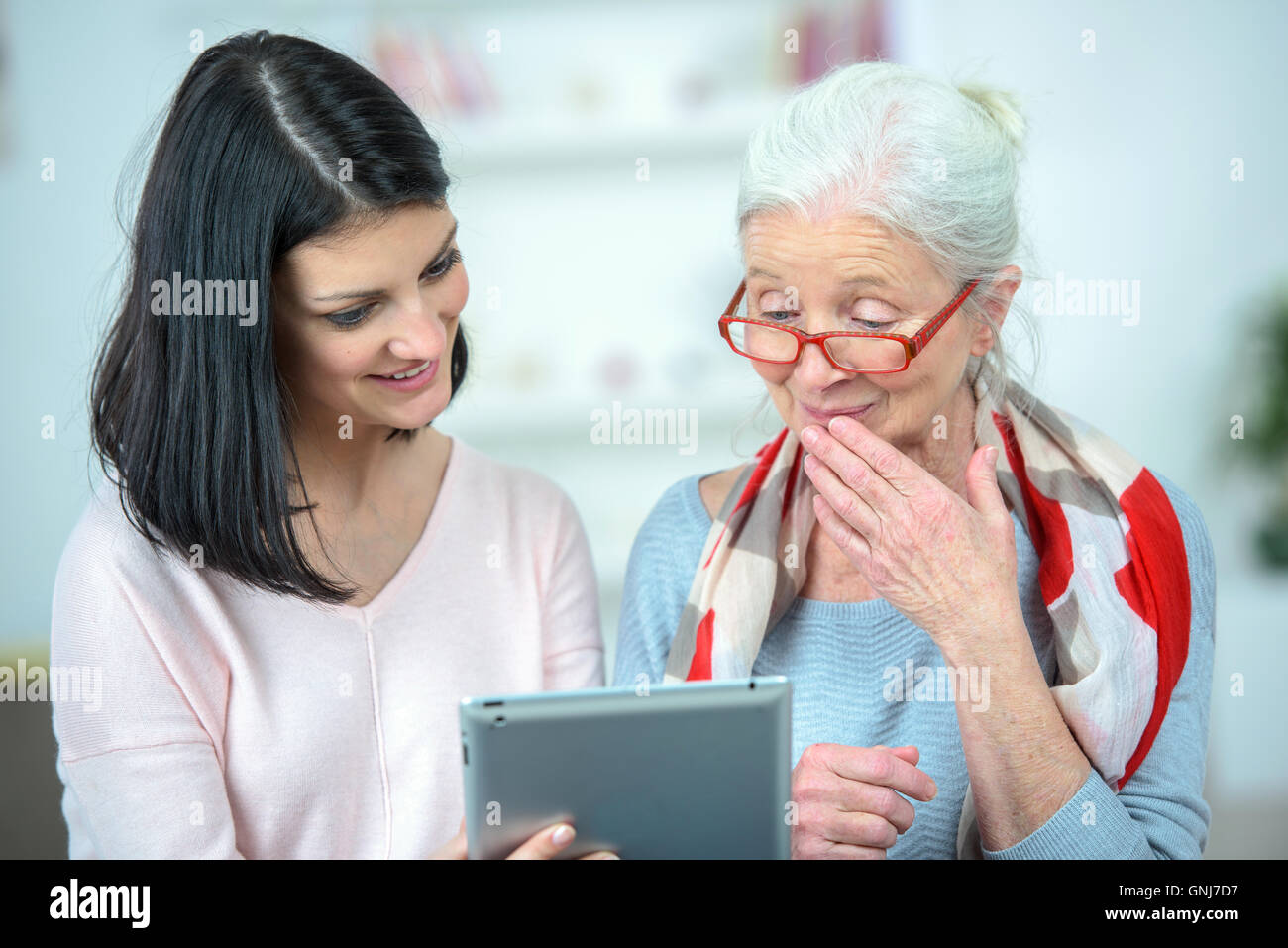Helping old woman use a tablet computer Stock Photo - Alamy
