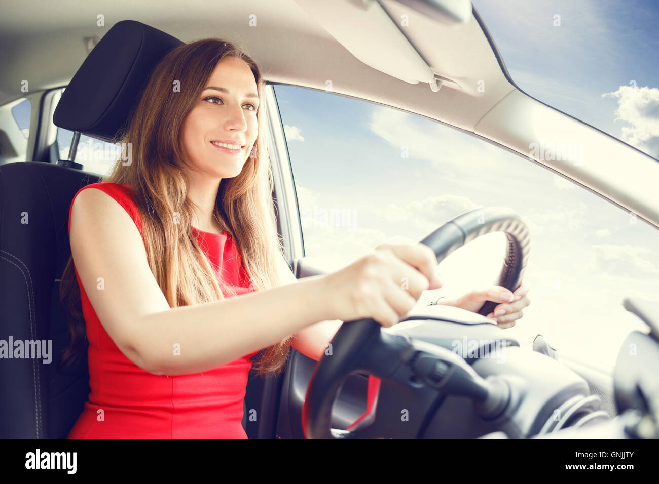 Young lady in red dress driving a car. Driving school background Stock ...