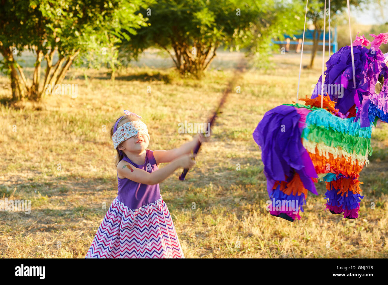 Young girl at an outdoor party hitting a pinata Stock Photo - Alamy