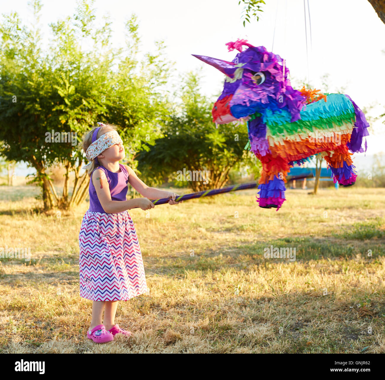 Young girl at an outdoor party hitting a pinata Stock Photo - Alamy