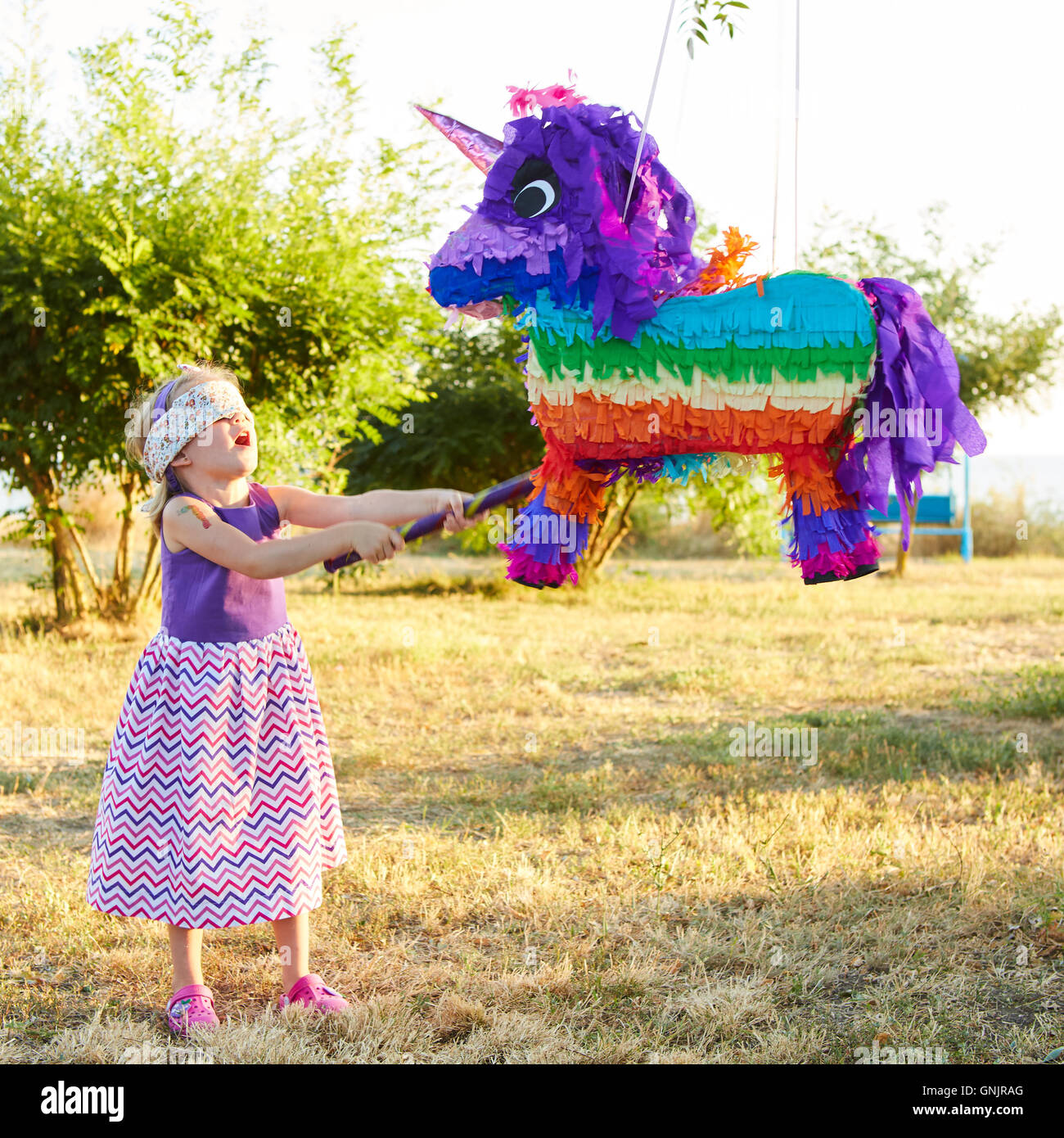 Young girl at an outdoor party hitting a pinata Stock Photo - Alamy
