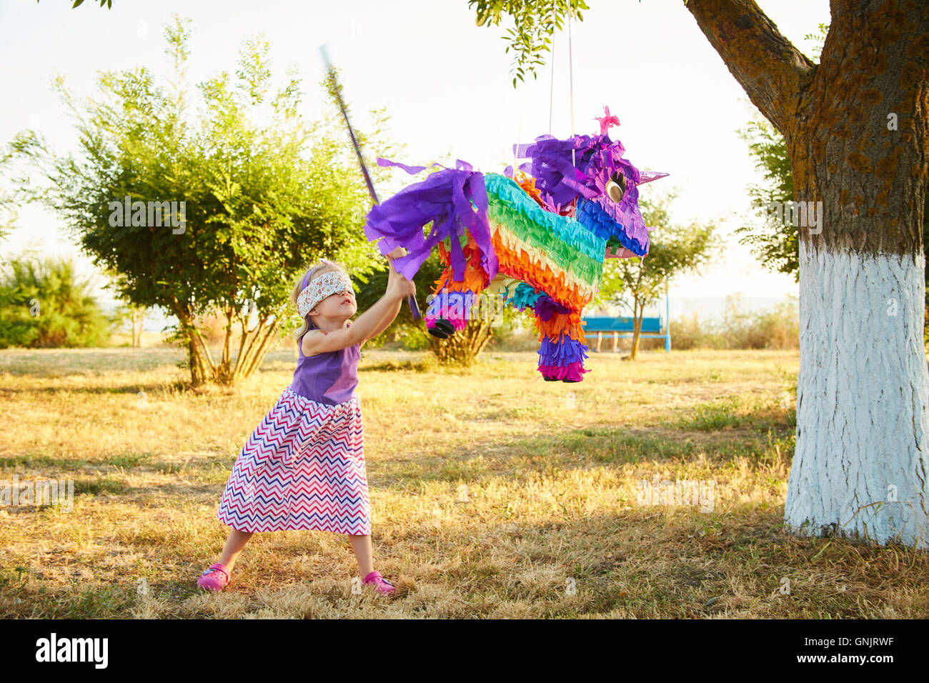 Young girl at an outdoor party hitting a pinata Stock Photo - Alamy