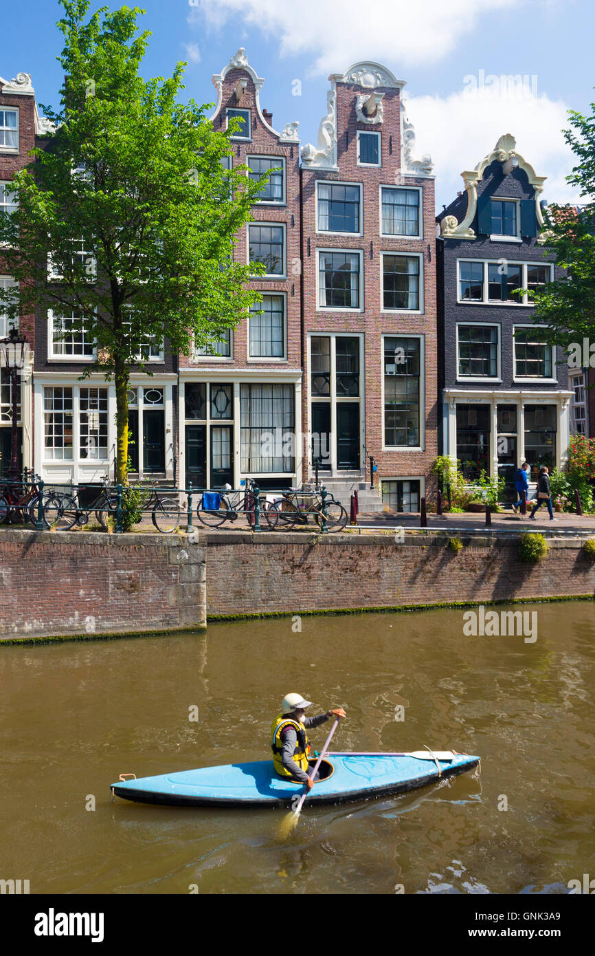 Tourist kayakking in single kayak by canalside gabled houses - Dutch ...