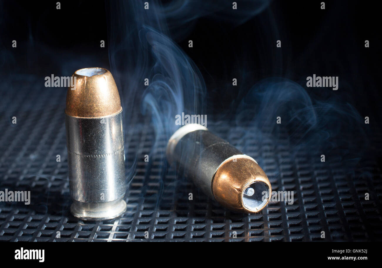 Smoke rising around a pair of handgun cartridges with hollow point ...
