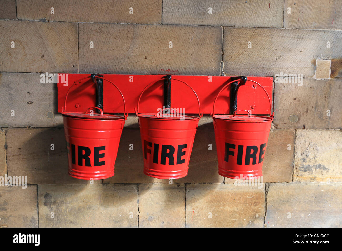 Three red fire buckets hanging on the wall in a heritage railway ...