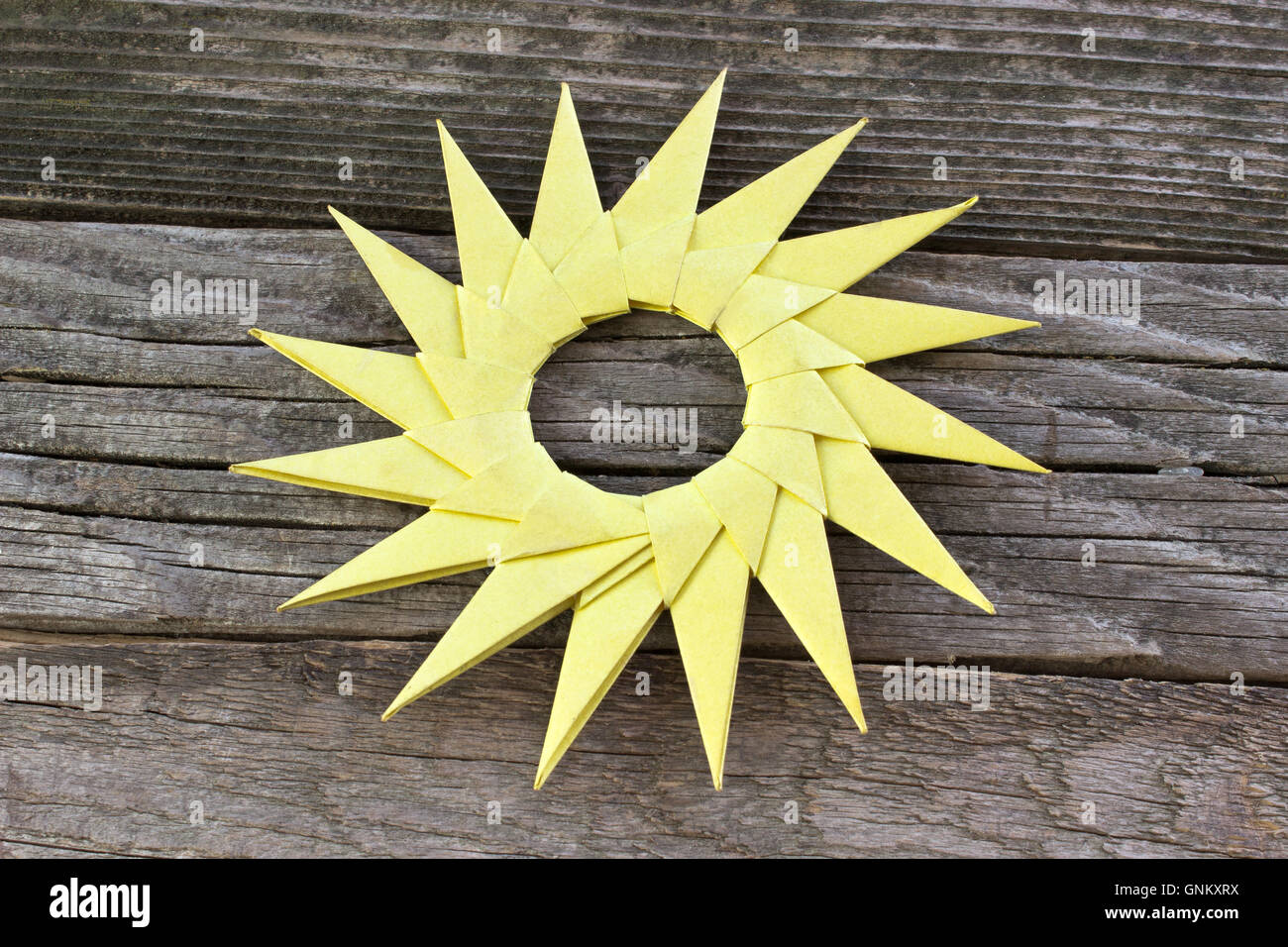 Origami yellow paper sun on wooden background Stock Photo - Alamy