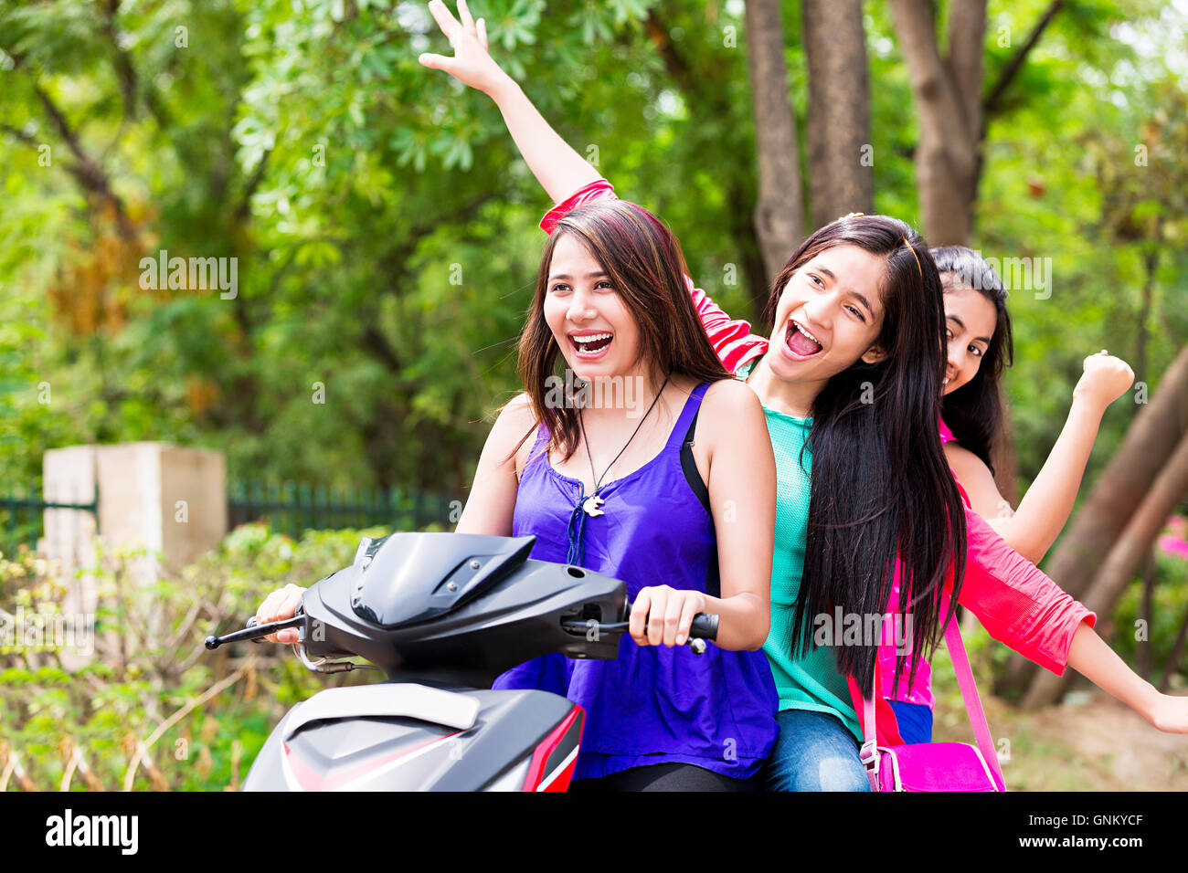 3 Young Girls Friends Park Riding Scooty enjoy Stock Photo - Alamy