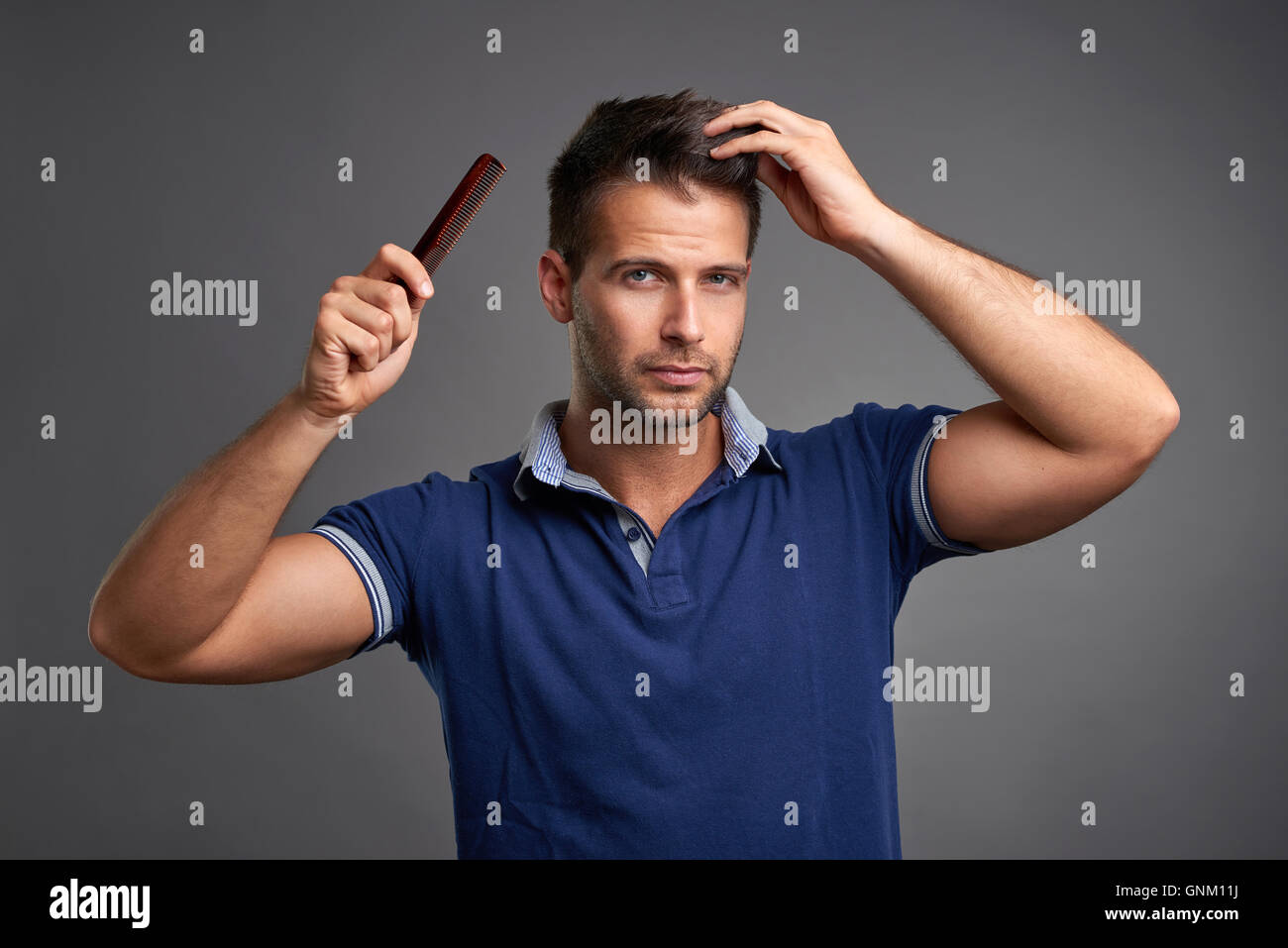 A serious handsome young man combing his hair Stock Photo - Alamy