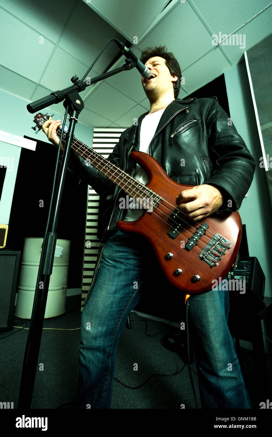 A Rock musician playing passionately bass in the rehearsal Studio Stock ...