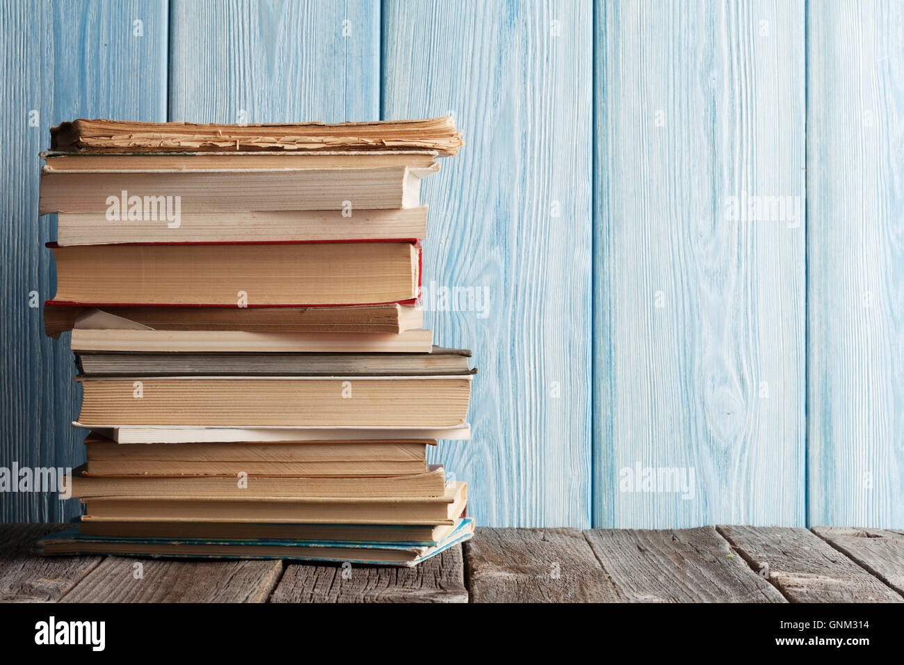 Stack of books on table in front of wooden wall. With copy space Stock ...