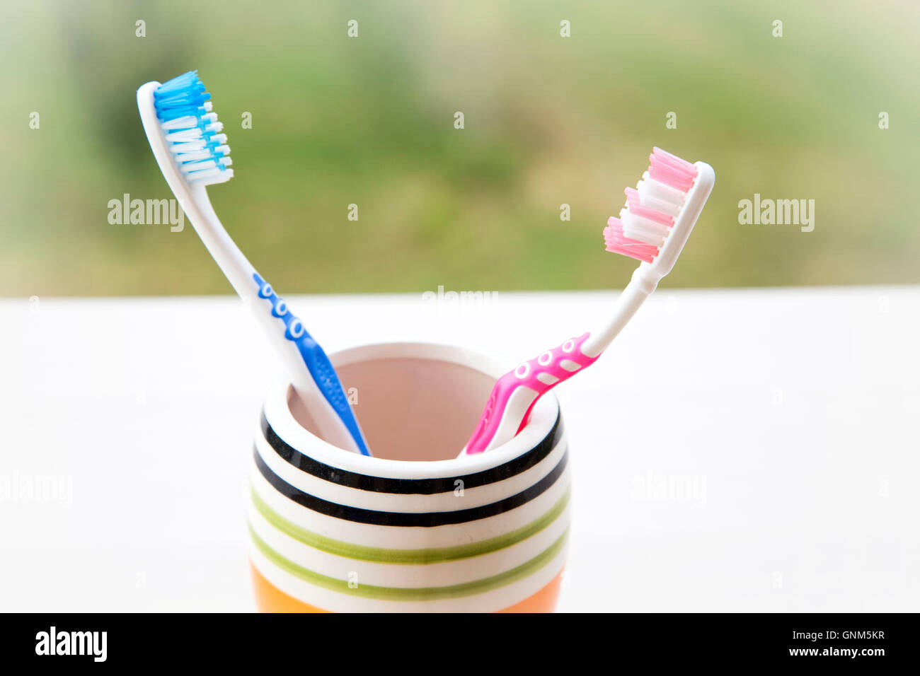 Tooth brushes in glass, his and hers Stock Photo - Alamy