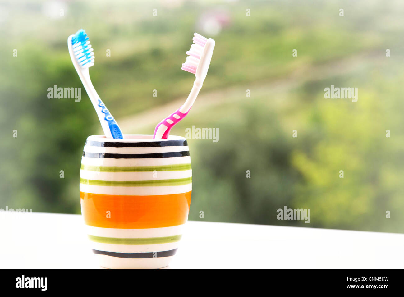 Tooth brushes in glass, his and hers Stock Photo - Alamy