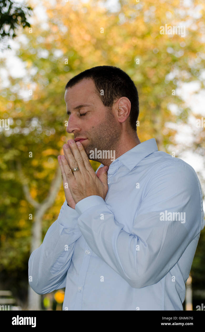 Married man praying outdoors on a fall day with fall colored leaves in ...