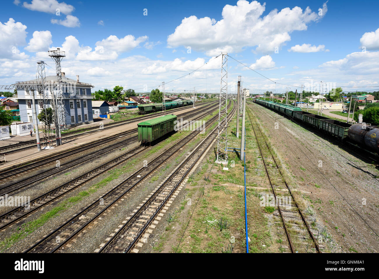 Train tracks at a local station in summer with blue sky and clouds ...