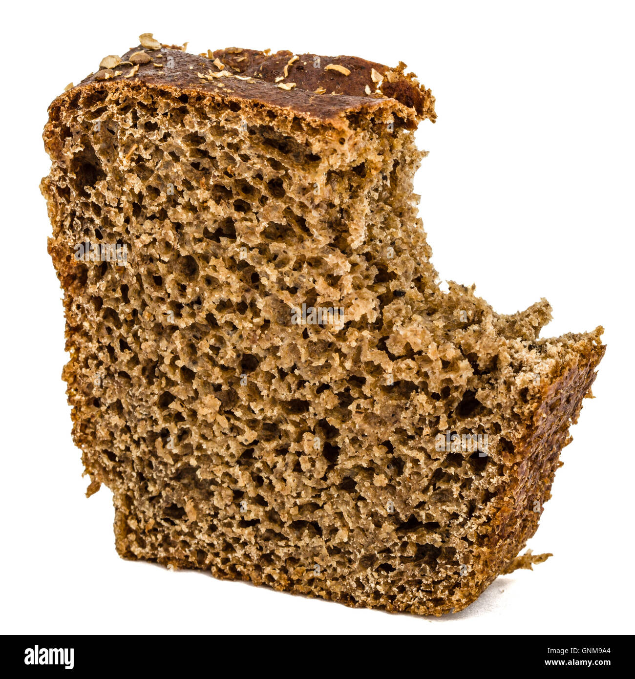 Bitten slice of bread made of dark flour, isolated on white background ...
