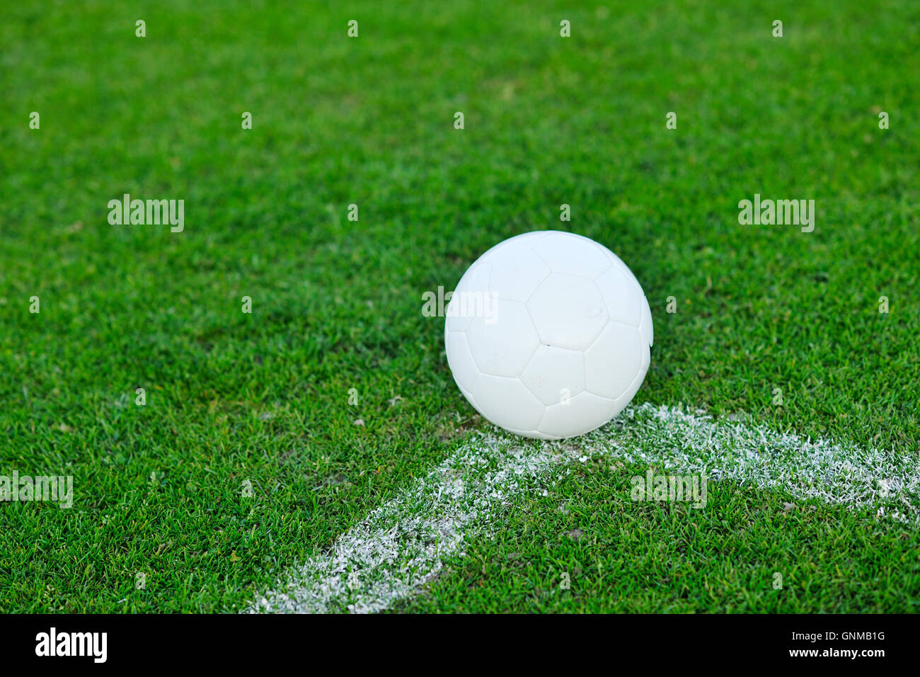 Soccer ball on grass at goal and stadium in background Stock Photo - Alamy