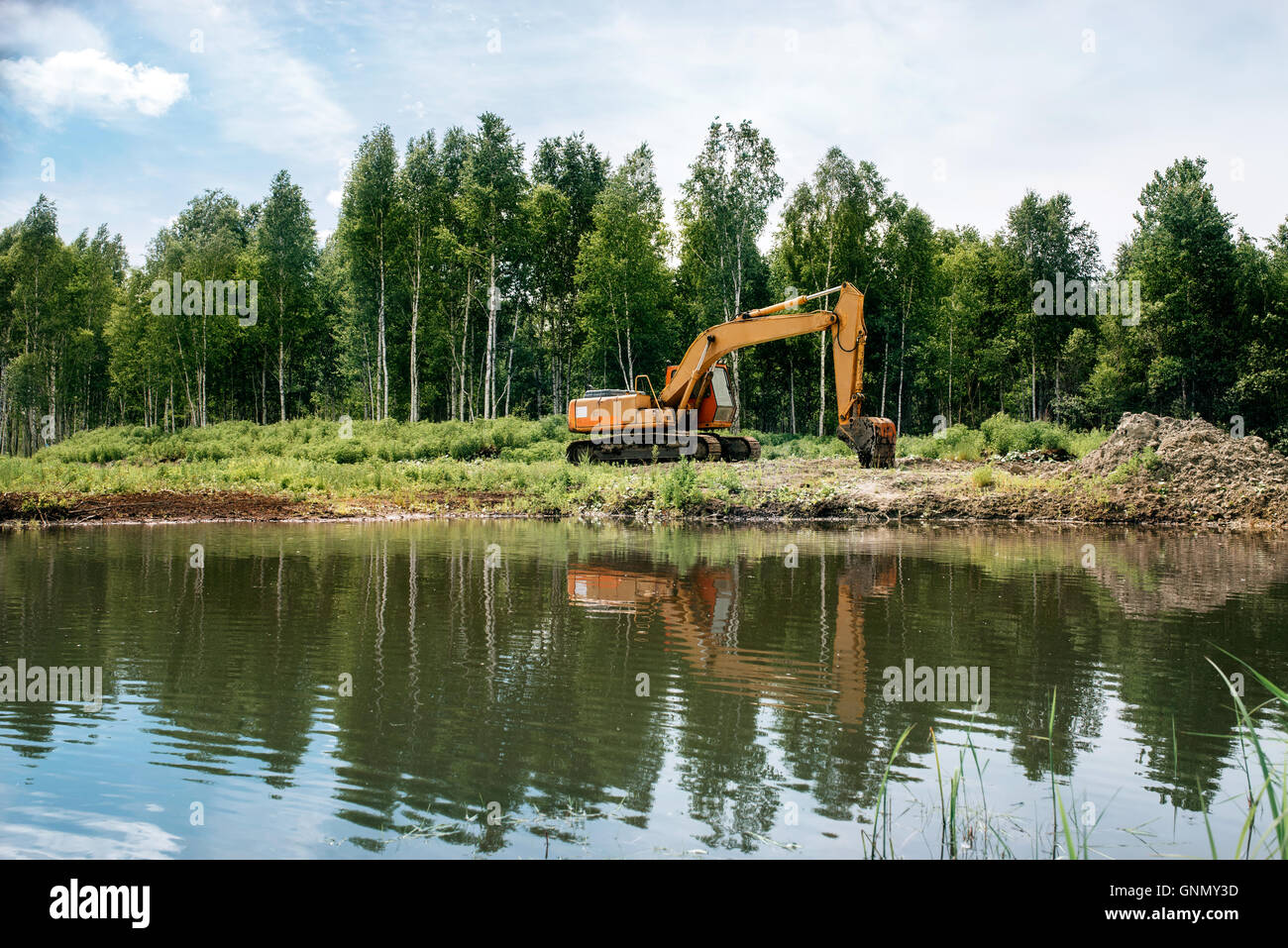 The excavator against a summer landscape Stock Photo - Alamy
