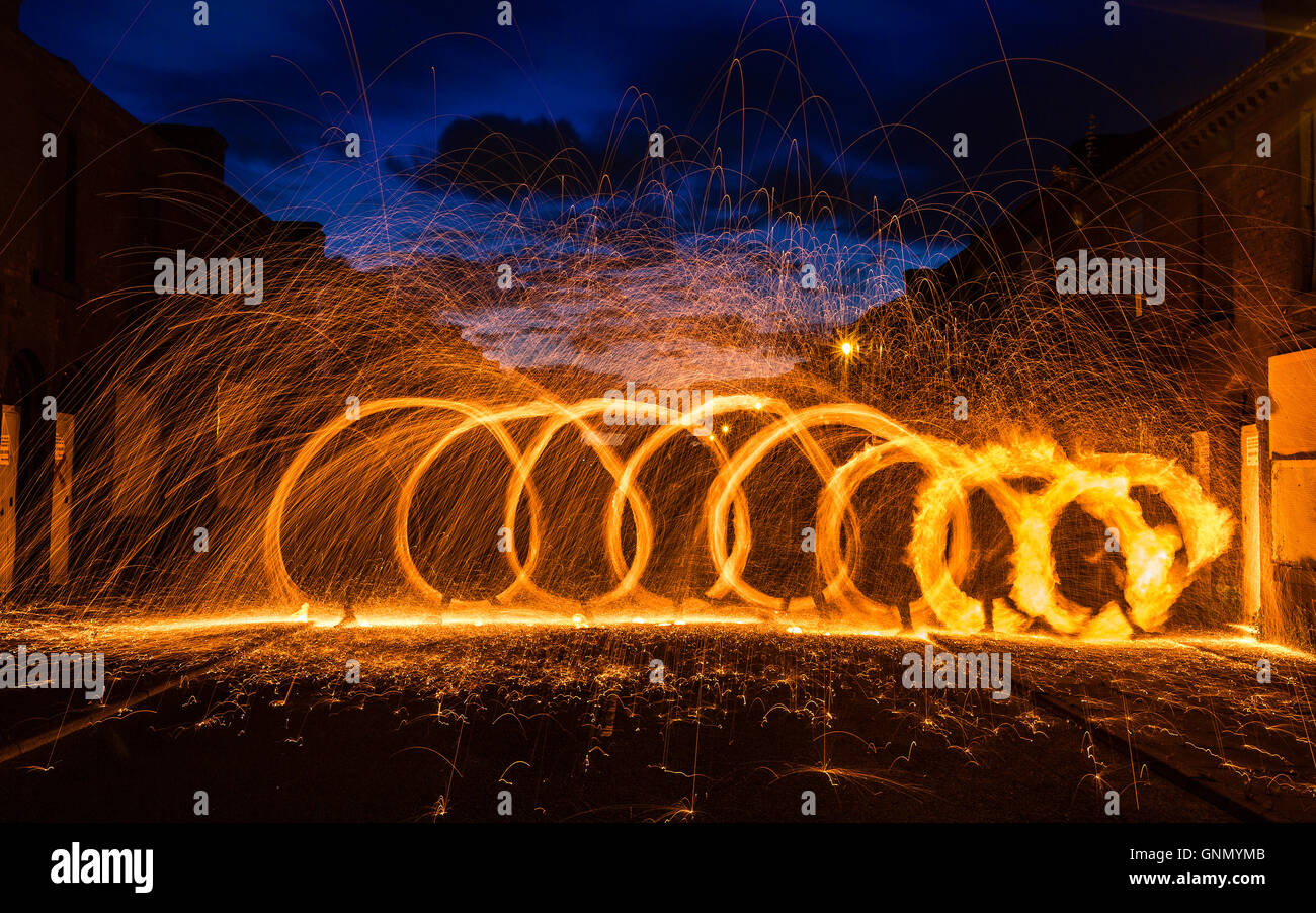 Wire wool fire dancing at twilight on abandoned urban street, sparks ...