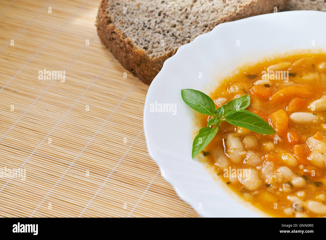 Cooked beans served in white plate with basil leaves and whole wheat ...