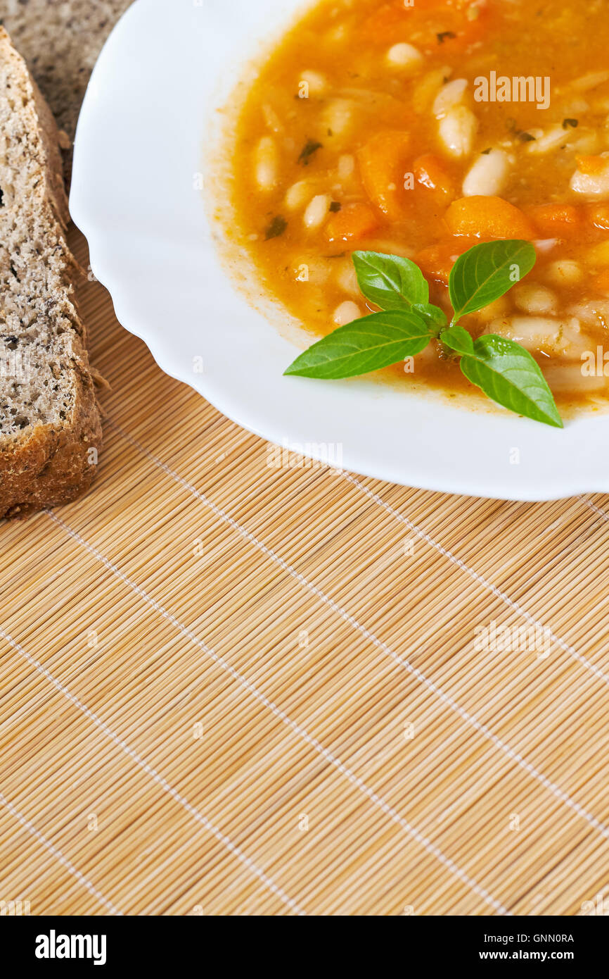 Cooked beans served in white plate with basil leaves and whole wheat ...