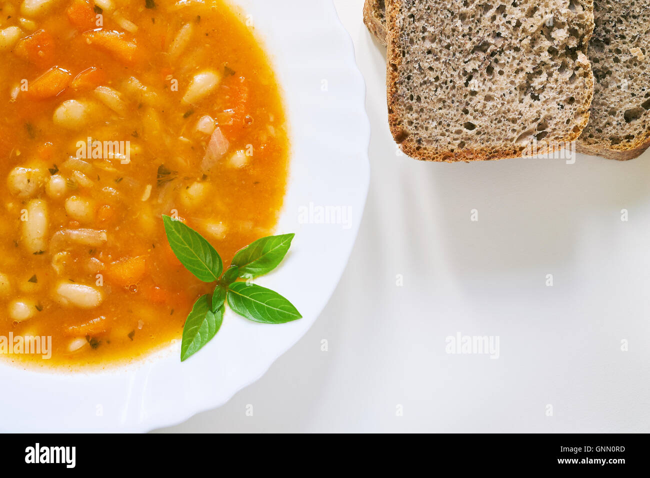 Cooked beans served in white plate with basil leaves and whole wheat ...